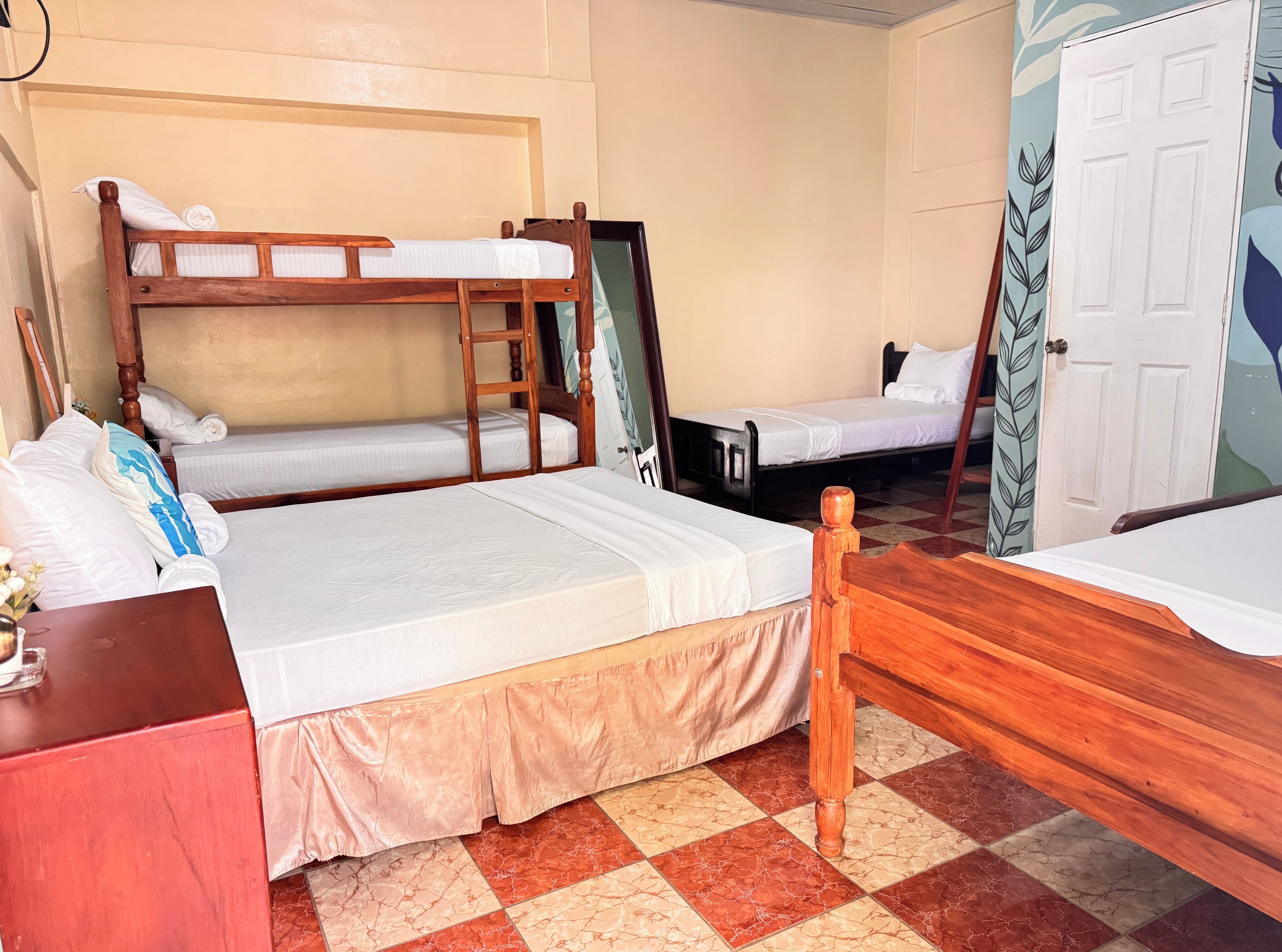 Quarto com uma cama de solteiro, uma cama individual, uma escrivaninha de madeira e uma porta com padrão de folha.