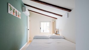 Quarto com cama, janela e ar-condicionado fixado na parede.
