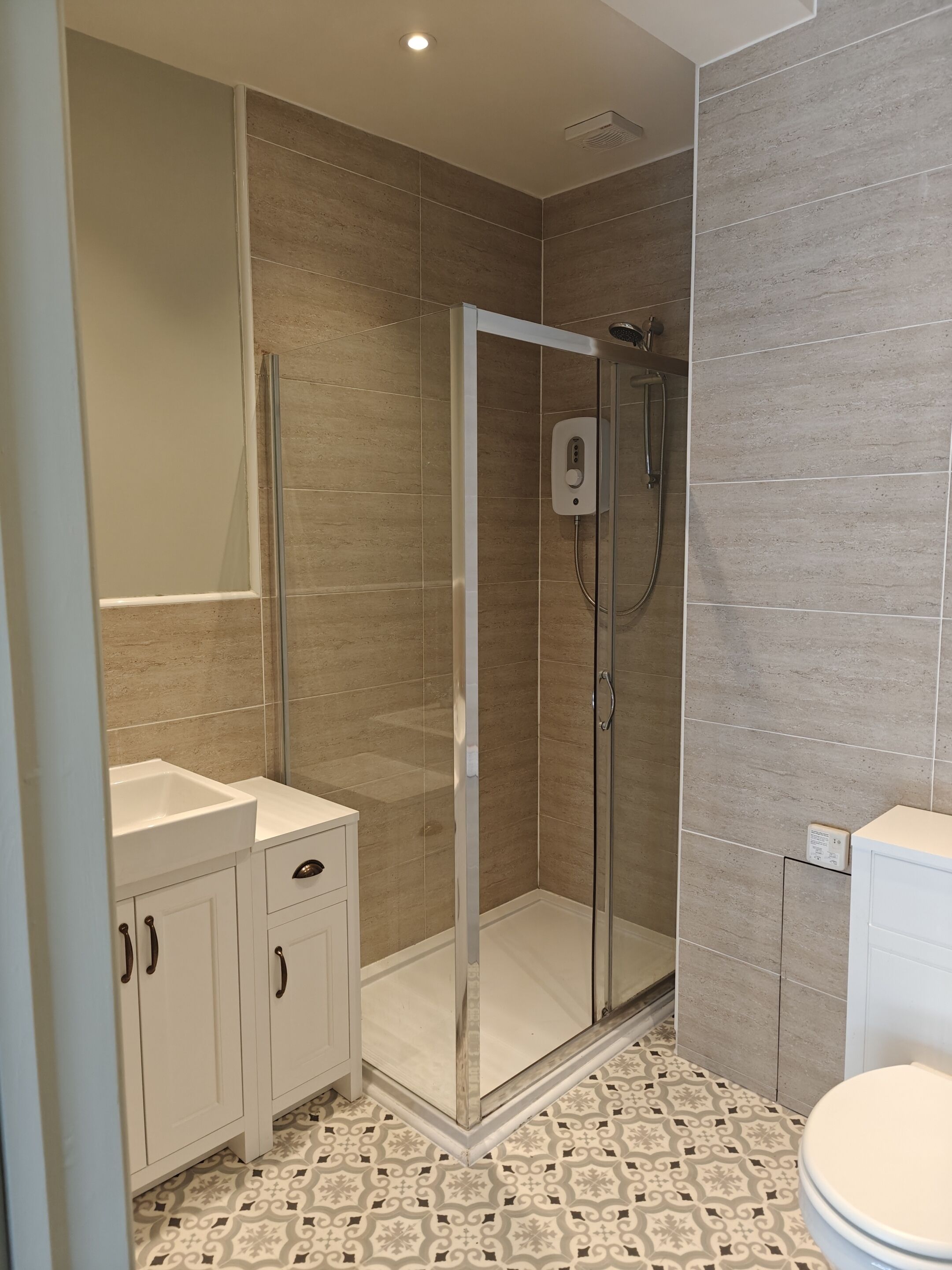 Um banheiro moderno com chuveiro de vidro, pia branca e vaso sanitário.