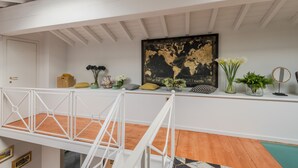 Quarto estilo loft com piso de madeira, grades brancas, uma grande pintura preta e dourada e diversos objetos decorativos em uma estante.