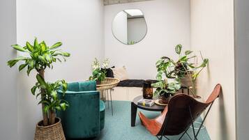 Um espaço de estar moderno e compacto, com claraboia, um espelho redondo e diversas plantas.