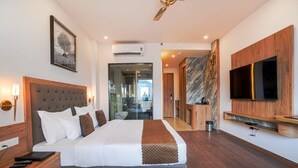 Quarto de hotel moderno com uma cama grande, televisão presa na parede e ventoinha no teto.