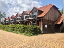 Uma fileira de cabanas de madeira com telhados vermelhos e varandas, cercada por vegetação.