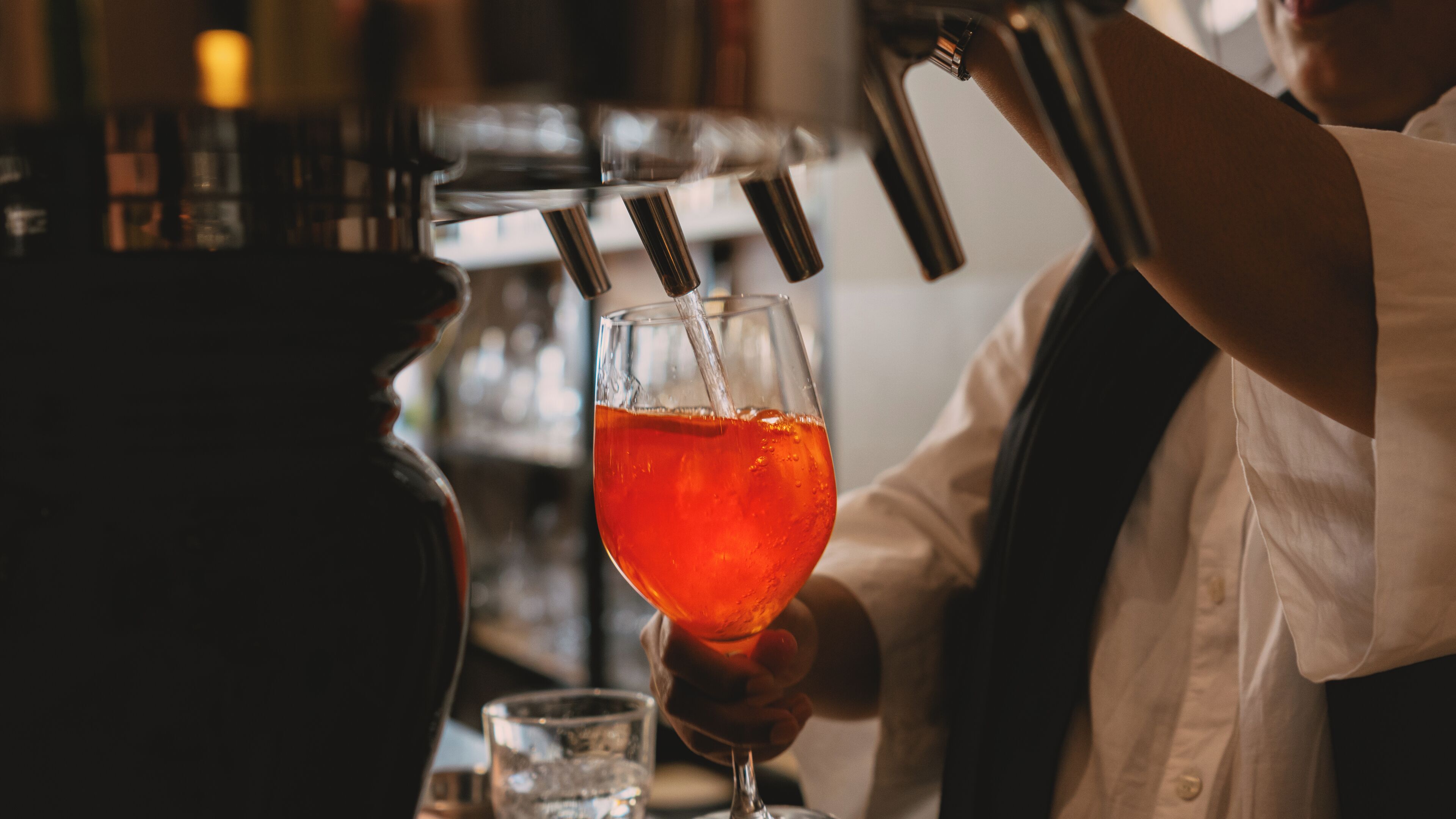 Um bartender a servir uma bebida num copo.