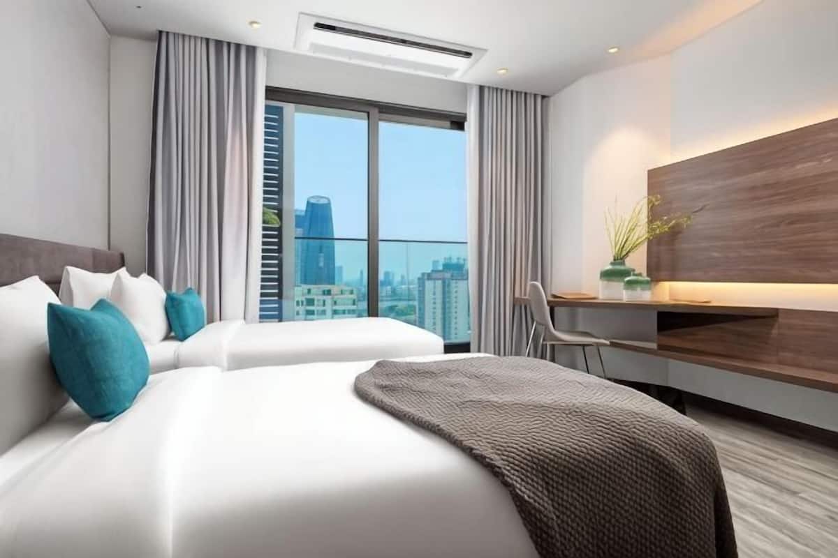 Quarto de hotel moderno com uma cama grande, uma escrivaninha e vista para a cidade.