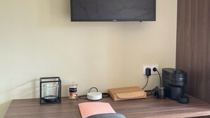 Um espaço de trabalho moderno com escrivaninha, cadeira, ar condicionado, televisão e máquina de café.