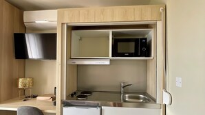 Uma cozinha compacta equipada com micro-ondas, fogão, pia e um pequeno frigorífico.