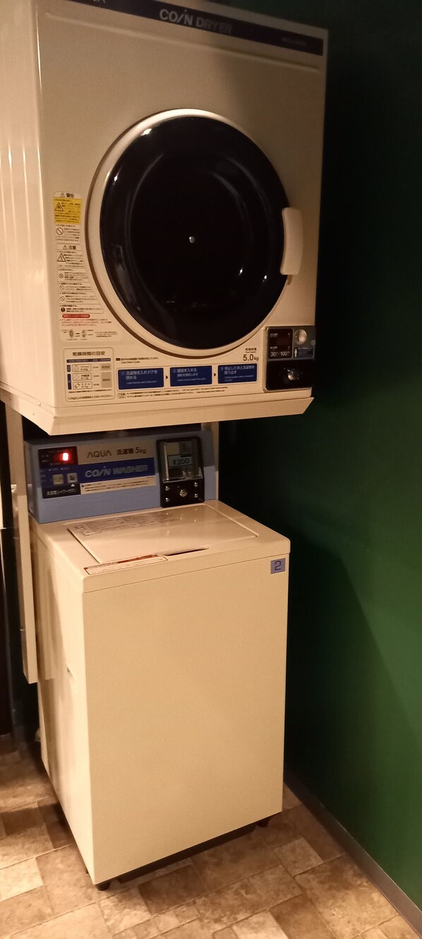 Máquina de lavar roupa de moedas com painel de controle e visor pequeno.