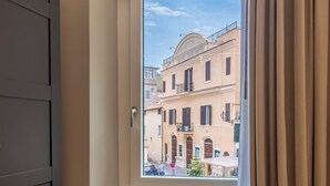 Quarto com janela, porta e vista para um edifício.
