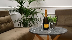 Uma mesa redonda com uma garrafa de champanhe, uma taça de vinho e uma pequena planta.