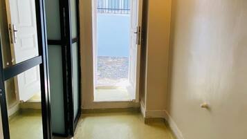 Corredor com vista para uma varanda, uma porta e um luminário.