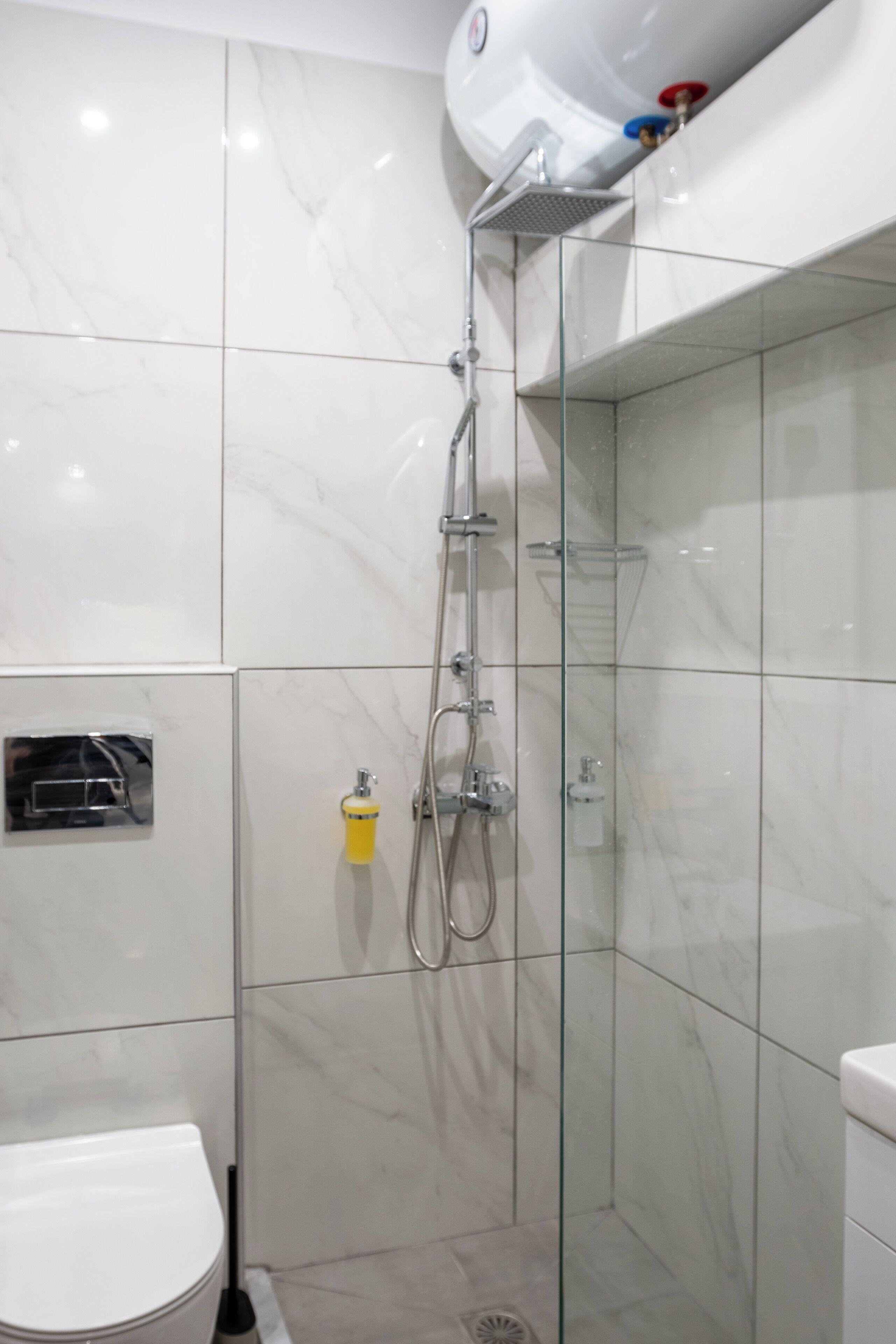 Uma casa de banho moderna com cabine de duche em vidro, sanita e lavatório.