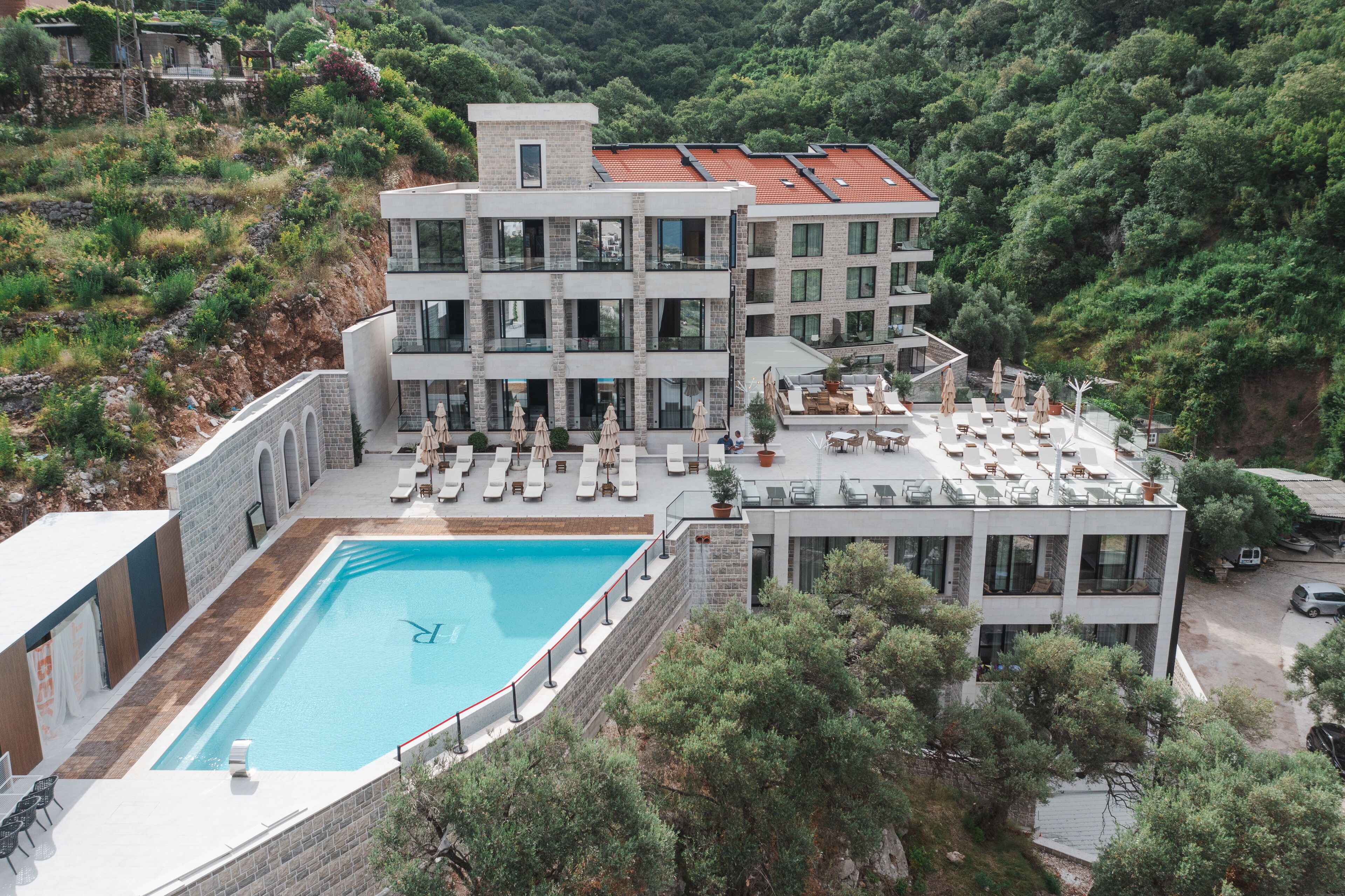 Um hotel moderno com piscina, área de estar externa e vista para as colinas ao redor.