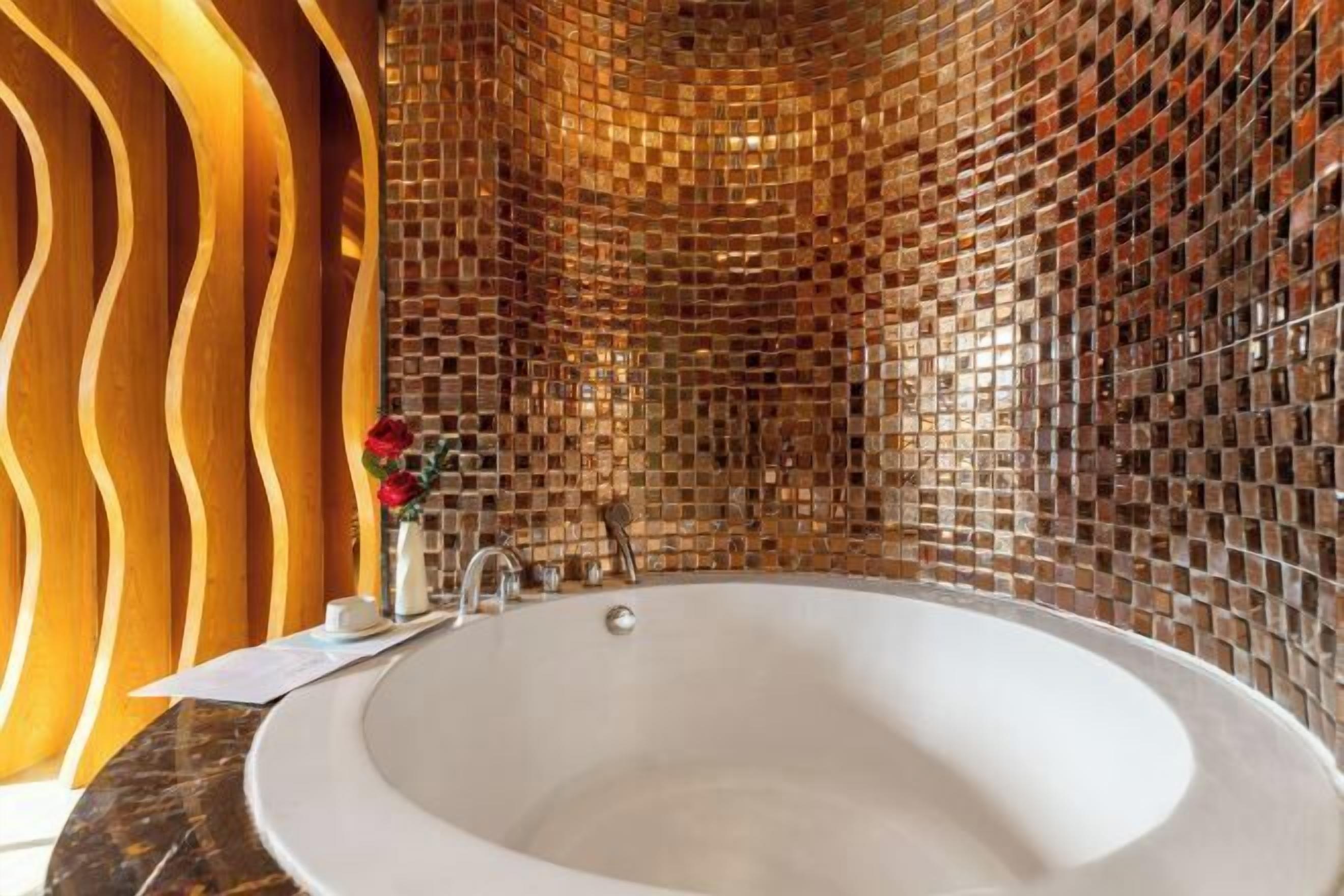 Um banheiro moderno com uma banheira grande, uma parede de madeira com design ondulado e uma parede revestida com mosaicos.