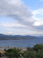 Vista costeira com corpo de água, montanhas ao longe e céu limpo.
