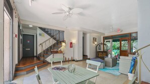 Uma sala de estar ampla com escada, mesa de jantar com cadeiras e um espaço de estar com sofás e mesa de centro.