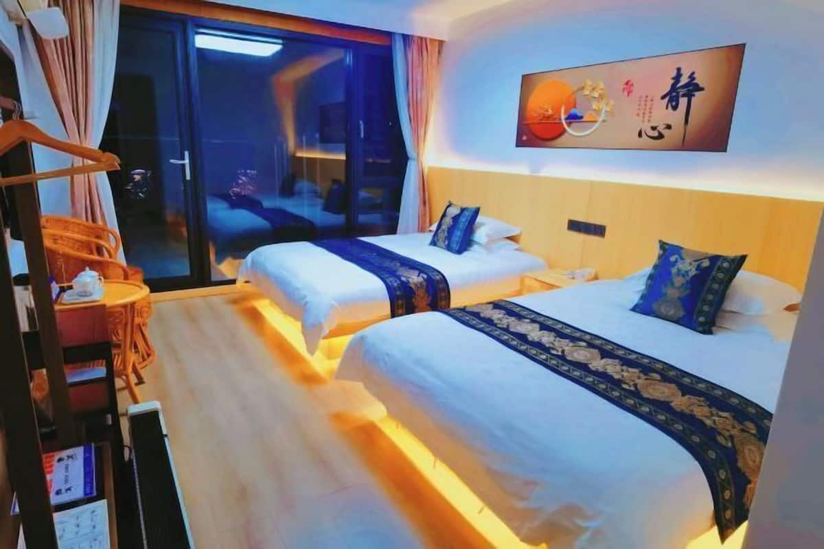 Quarto de hotel com duas camas, uma janela grande e uma obra de arte pendurada na parede.