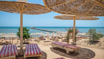 Uma praia privada, espreguiçadeiras, guarda-sóis de praia