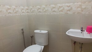 Uma casa de banho com sanita, lavatório e chuveiro.
