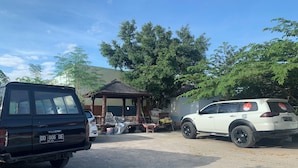 Uma área de estacionamento com dois carros, um gazebo e uma grande árvore.