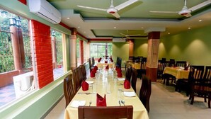 Uma sala de jantar com uma mesa comprida posta para refeição, rodeada de cadeiras.