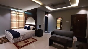 Um quarto moderno com cama, sofá, mesa de cabeceira e um espelho grande.