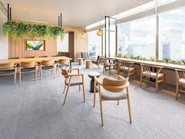 Um espaço de escritório moderno com uma mesa comprida, várias cadeiras e uma grande janela com vista para a cidade.