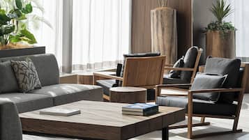 Uma sala de estar moderna com um sofá cinzento, mesa de centro de madeira e duas poltronas de couro. Há plantas em vasos e uma grande parede de destaque em madeira.