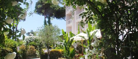 Um caminho no jardim leva a um edifício com fachada branca e varandas.