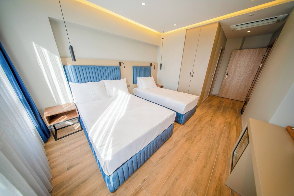 Quarto de hotel moderno com uma cama grande, uma cama menor e um guarda-roupa.