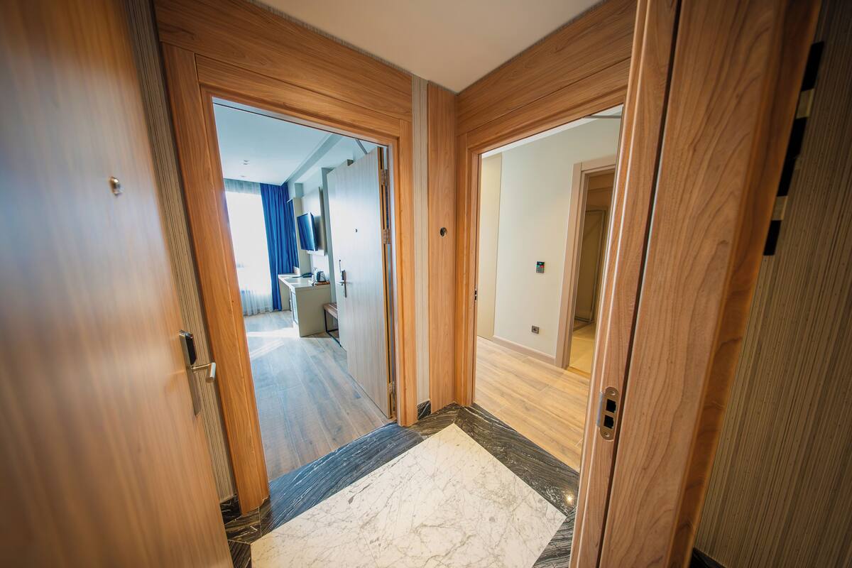 Um corredor com paredes de madeira e chão de mármore, que leva a um quarto com cama e janela.