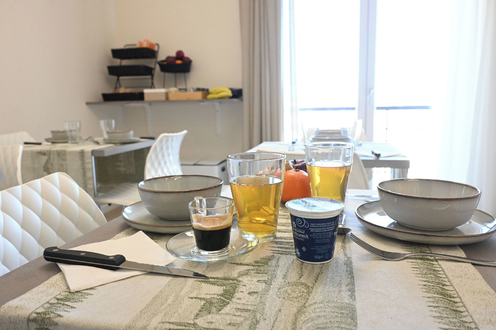 Uma mesa de jantar posta com tigelas, copos e uma faca.