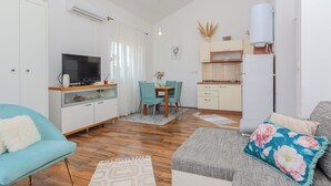 Uma sala de estar moderna com um sofá, uma televisão e uma área de jantar com cadeiras e uma mesa.