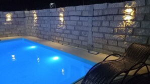 Piscina ao ar livre com muro de tijolos e iluminação embutida.
