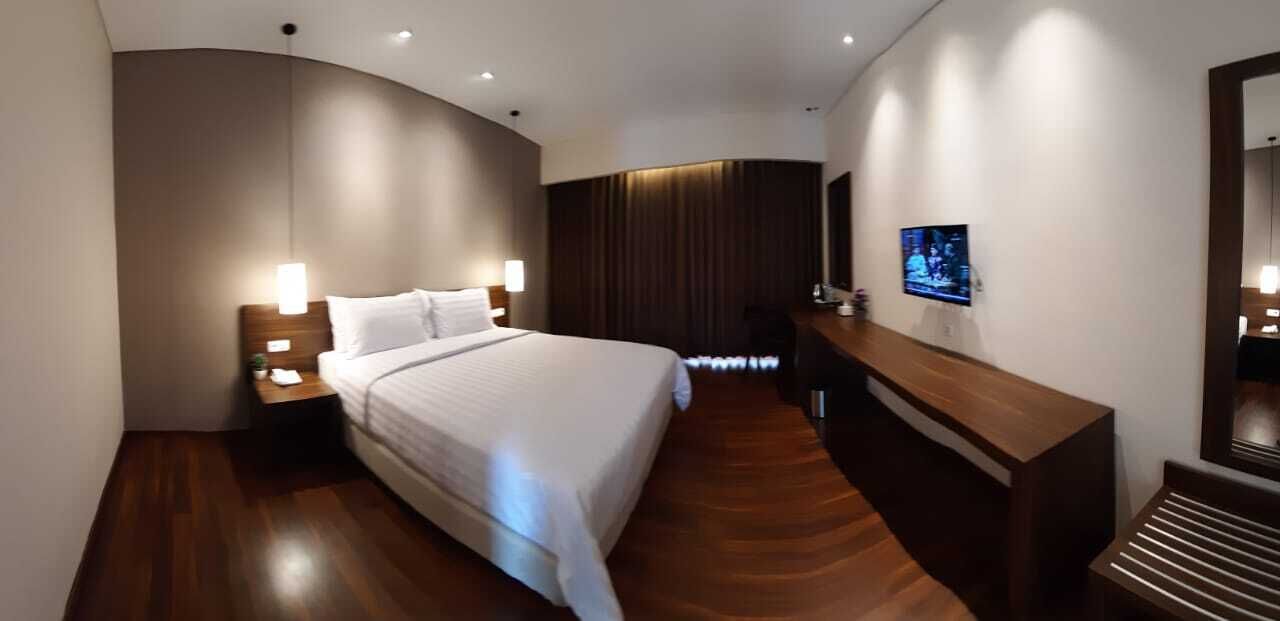 Quarto de hotel moderno com uma cama grande, uma escrivaninha e uma televisão.
