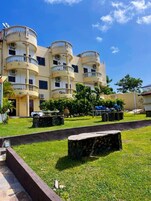 Um edifício com várias andares, varandas e um pátio ajardinado.