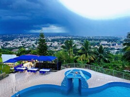 Área de piscina com escorregador, assentos externos e vista para a paisagem urbana.