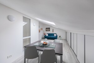 Uma área de refeições moderna com uma mesa de vidro, duas cadeiras e um objeto decorativo central.