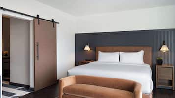 Quarto moderno com uma cama grande, um sofá marrom, uma porta deslizante e duas luminárias de cabeceira.
