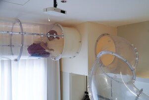 Um quarto com estruturas cilíndricas transparentes, possivelmente para escalada ou exercício.