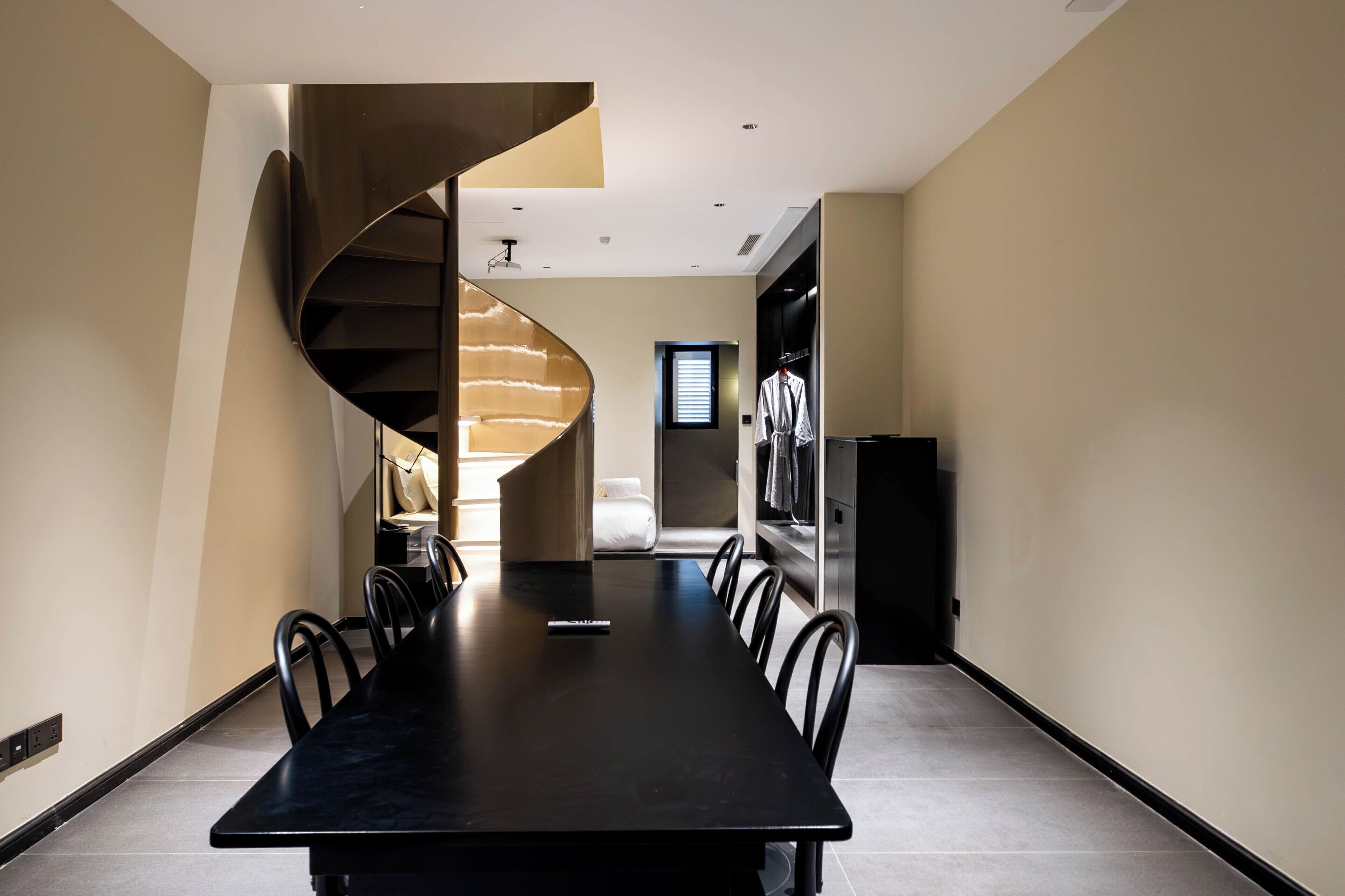 Quarto de hotel moderno com escada em espiral, mesa de jantar comprida e closet espaçoso.