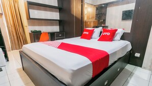 Quarto de hotel moderno com uma cama grande, mesa de cabeceira, escrivaninha e guarda-roupa.