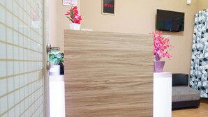 Balcão de recepção com painel de madeira, planta em vaso e um letreiro com a palavra "OYO".