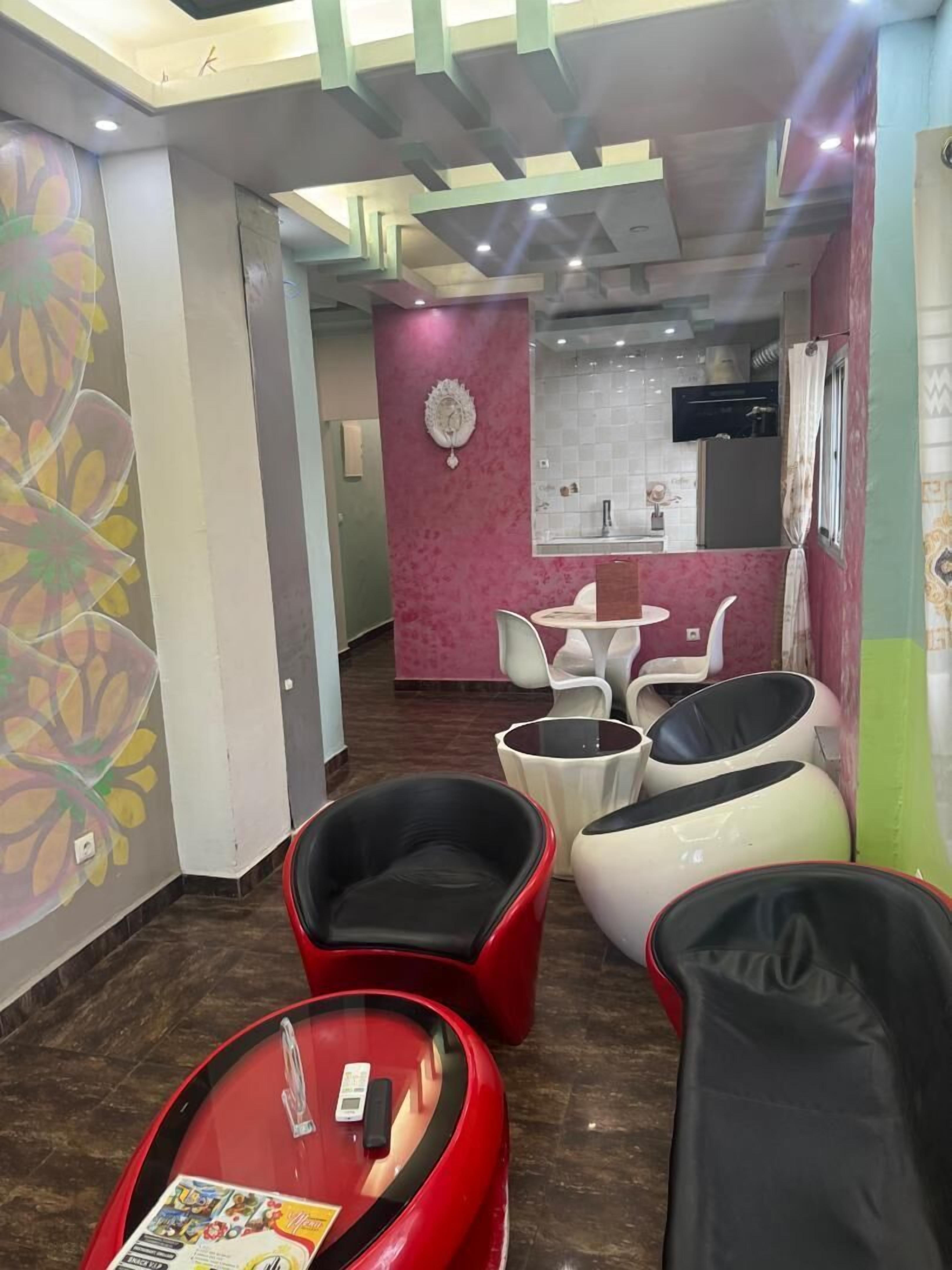 Um interior moderno com área de recepção, espaço para refeições e área de descanso com cadeiras e uma mesa.