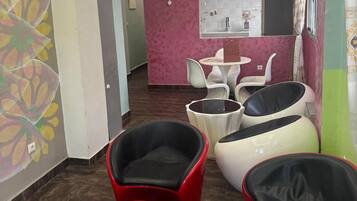 Um interior moderno com área de recepção, espaço para refeições e área de descanso com cadeiras e uma mesa.