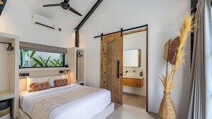 Quarto moderno com uma cama grande, porta de madeira, espelho e vista para o verde pela janela.