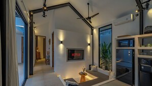 Uma sala de estar moderna com televisão de tela plana, ventilador de teto e ar condicionado instalado.