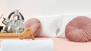 Um quarto aconchegante com uma cama, almofadas e um tabuleiro com chaleira e bule.
