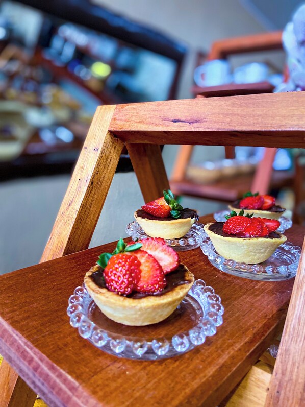 Três tartes de chocolate com morangos sobre uma mesa de madeira.