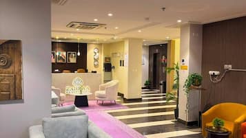 Um saguão de hotel com balcão de recepção, área de estar e balcão de check-in.